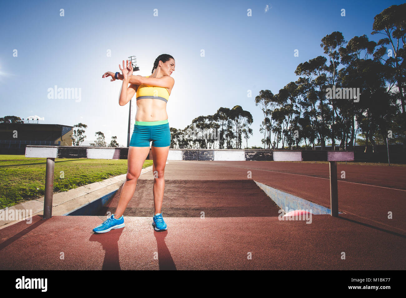 Female fitness model and track athlete sprinting on an athletics track ...