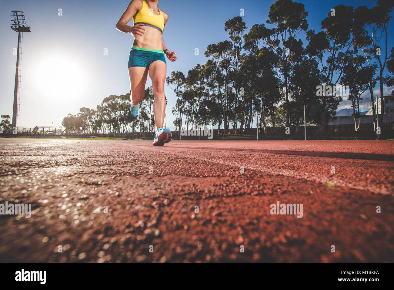 Female fitness model and track athlete sprinting on an athletics track ...
