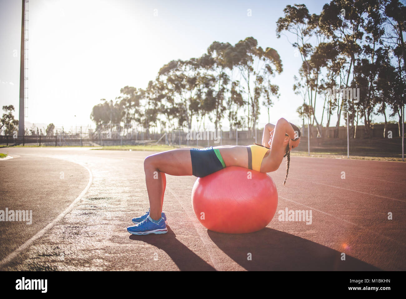 Female fitness model doing exercises outside at a sport stadium on a ...