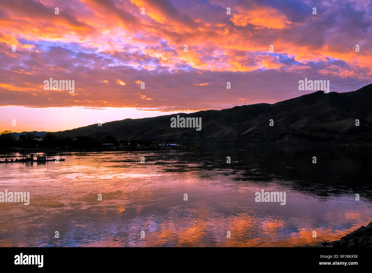 Dramatic sunset landscape with lake, sky reflection, fishing boat and ...