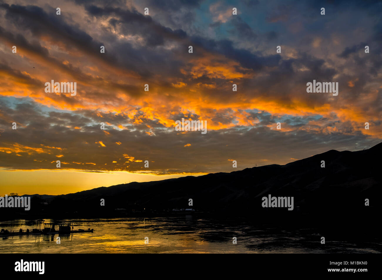 Dramatic sunset landscape with lake, sky reflection, fishing boat and ...