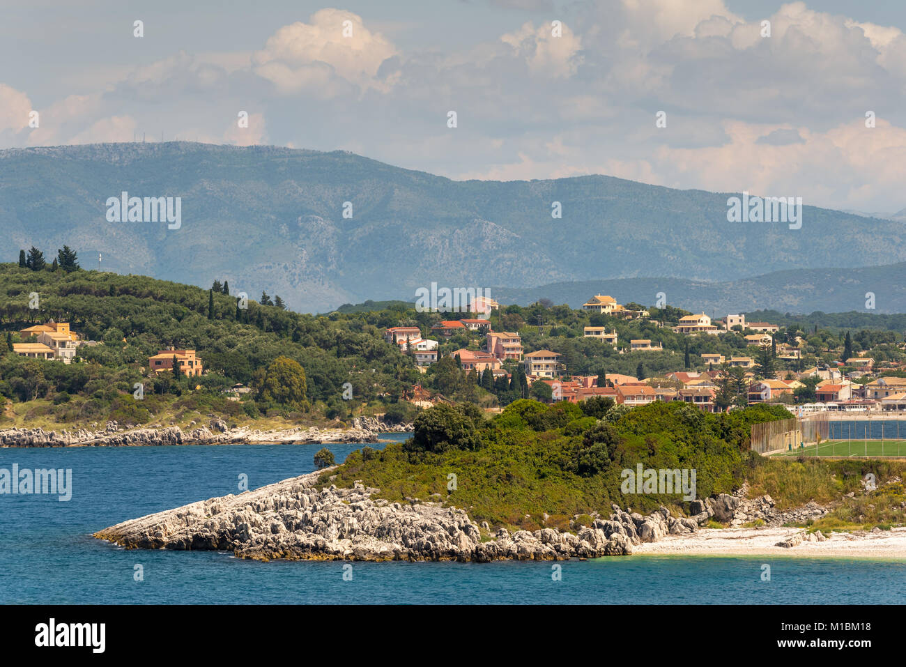A view Kassiopi village with houses on the hills. North east coast of ...