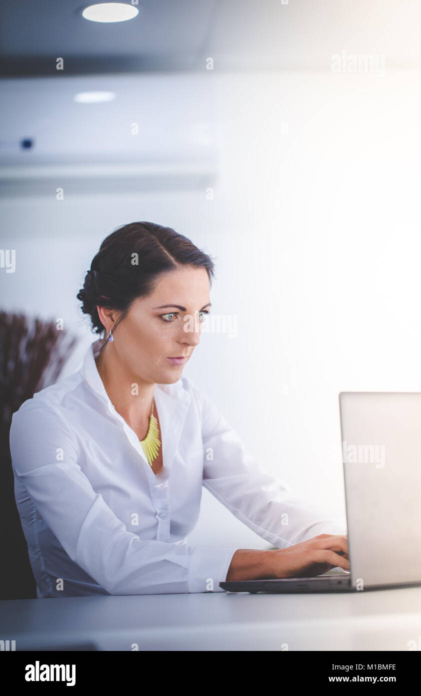 Beautiful brunette female business woman working on her laptop in her ...