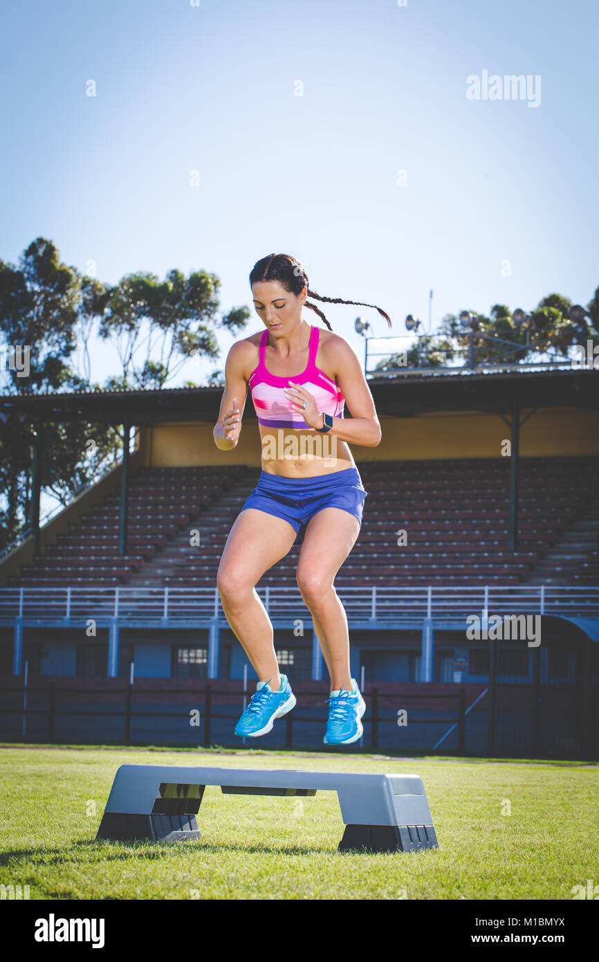 Female fitness model doing exercises outside at a sport stadium on a ...