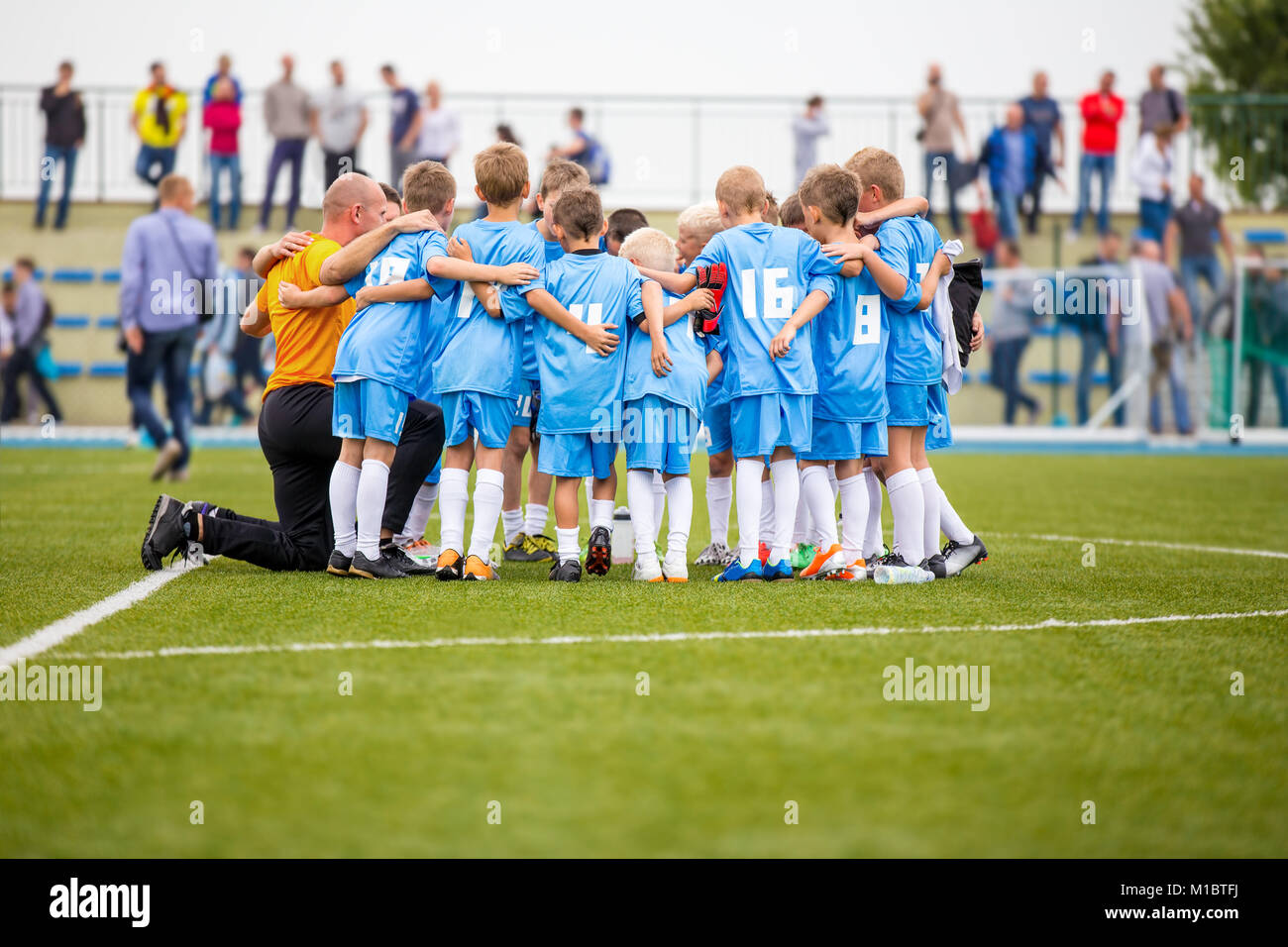 Children soccer football team with coach. Group of kids standing together on the pitch. Coach ...
