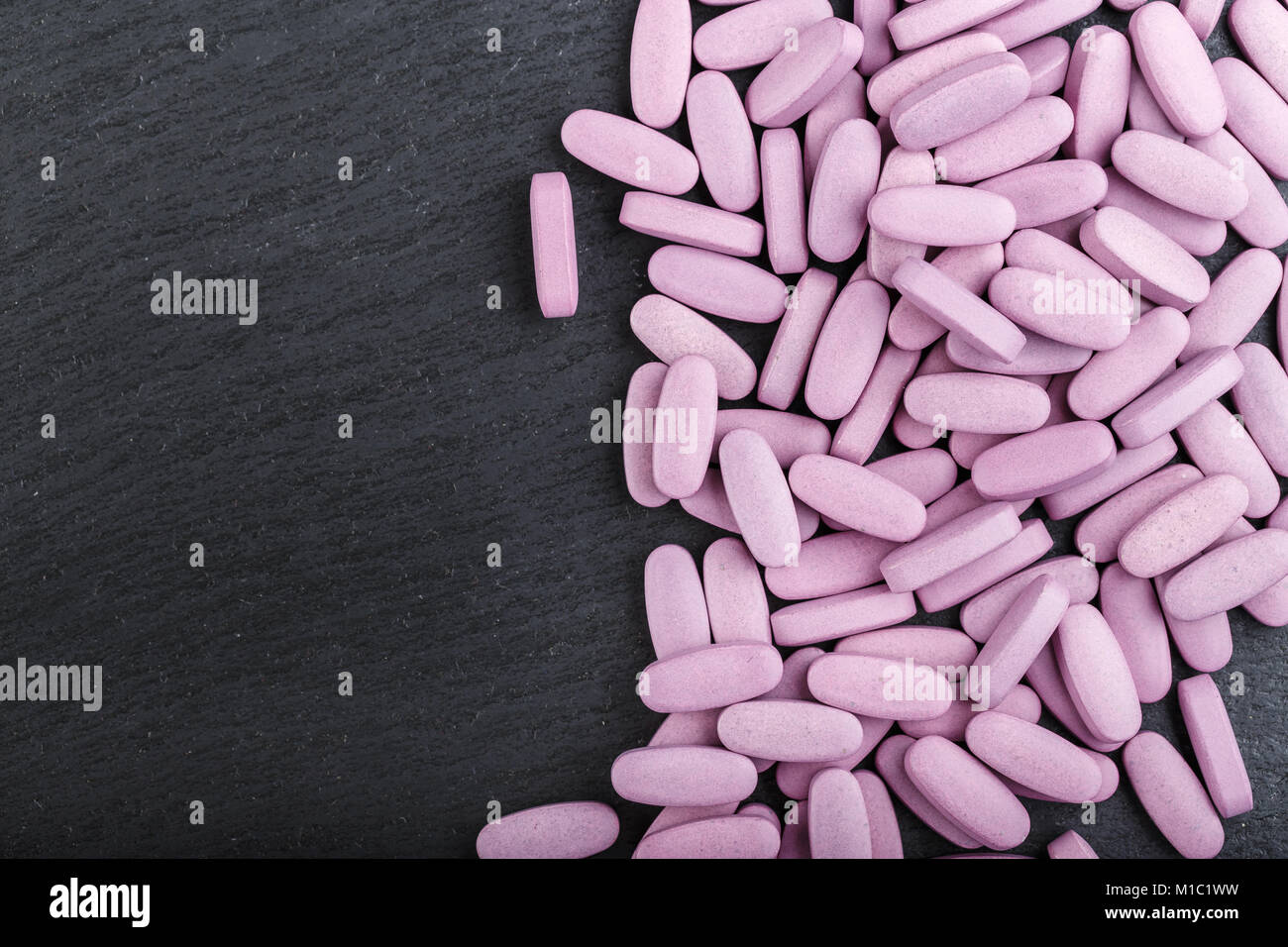 large pink tablets scattered on a black background Stock Photo - Alamy