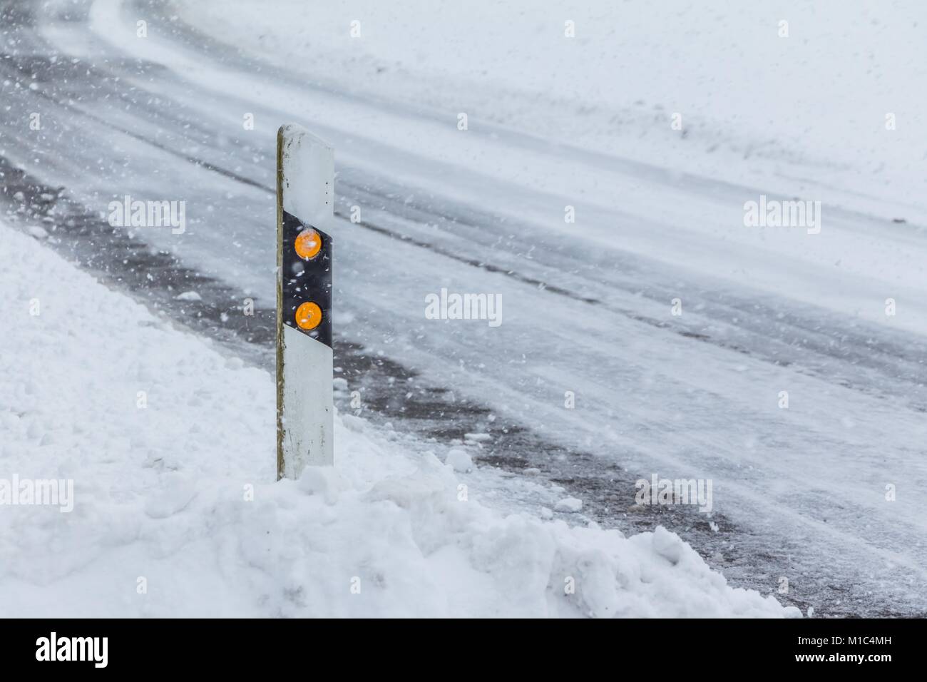 Reflector post at snowy white snow blizzard car winter road. The street ...