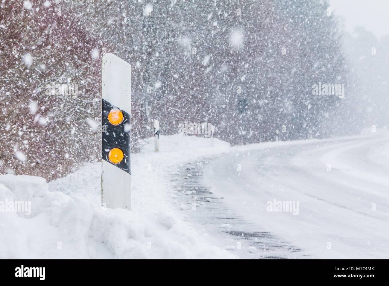 Reflector post at snowy white snow blizzard car winter road. The street ...