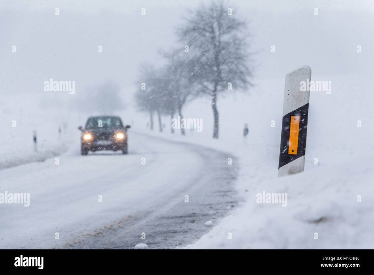 Reflector post at snowy white snow blizzard car winter road. The street ...