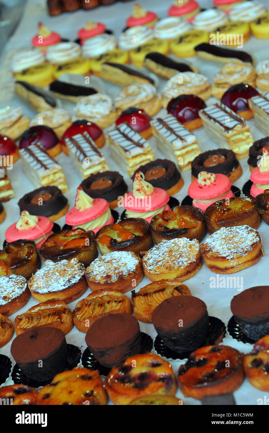 A selection of colourful artisan bakery cup cakes in rows or lines on a ...