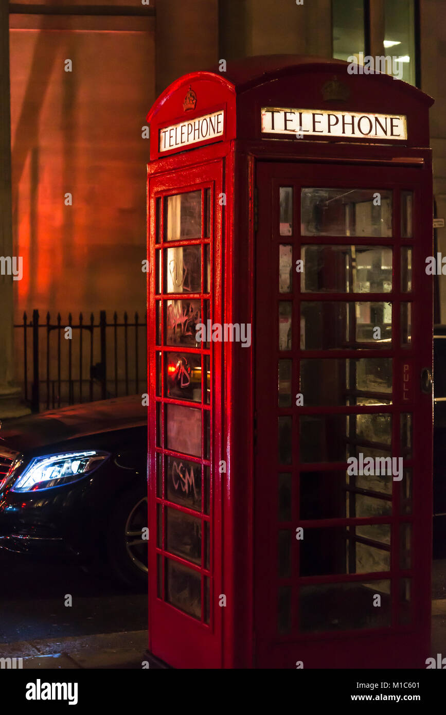Red telephone box and posh car behind it at night, London, UK Stock ...