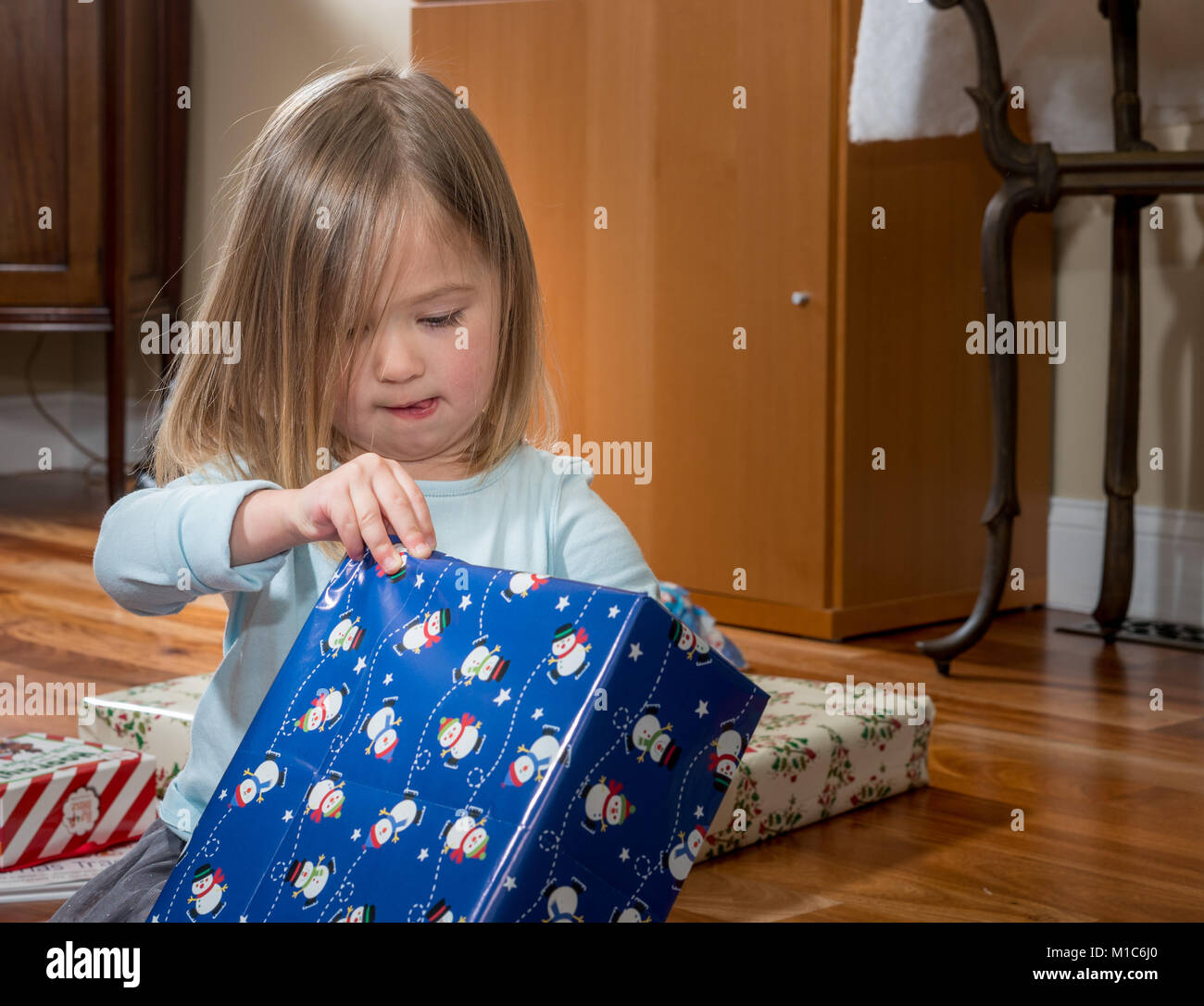 Young female caucasian girl opening presents Stock Photo - Alamy