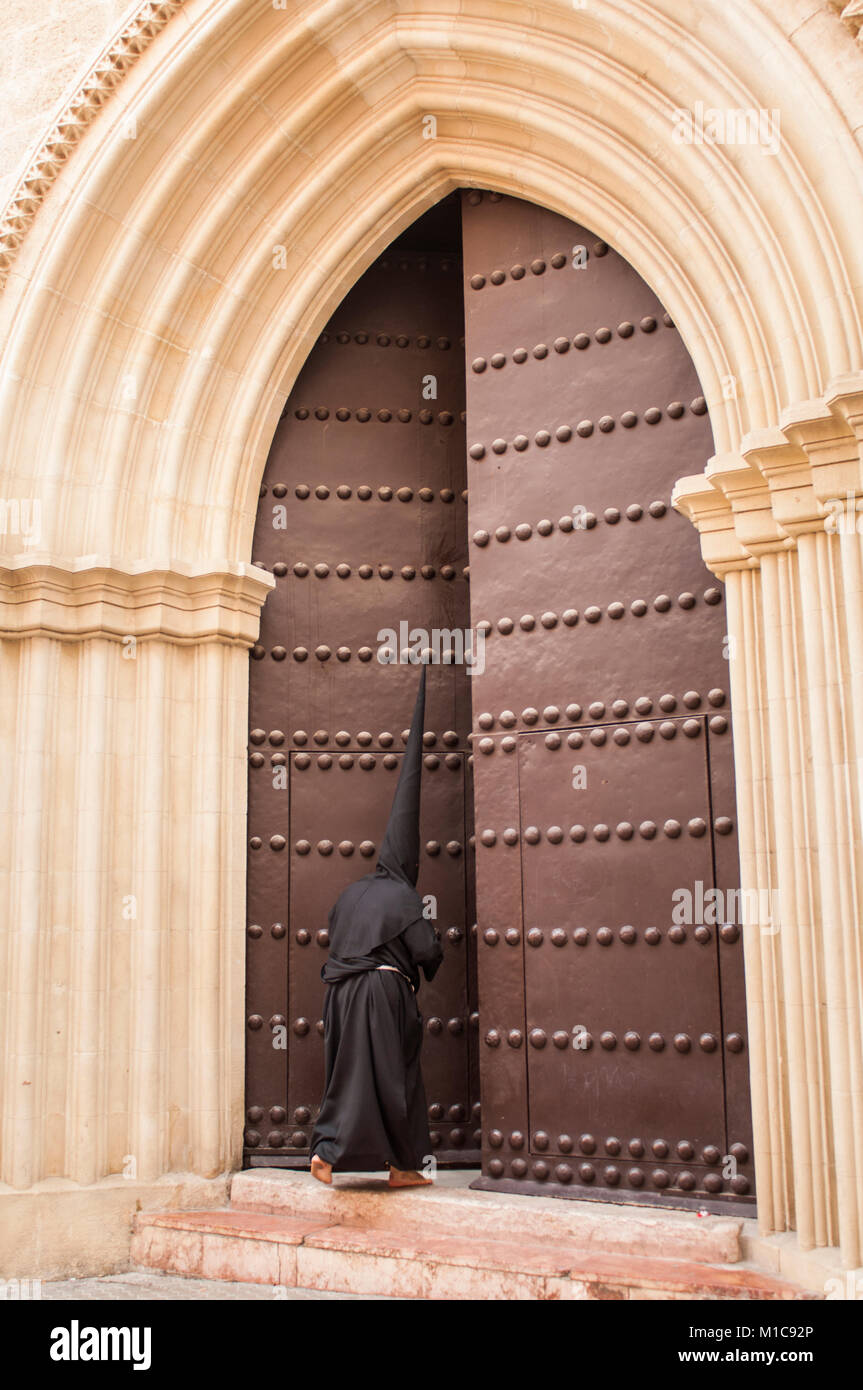Penitent of the brotherhood of "Santa Marta" entering the church before ...
