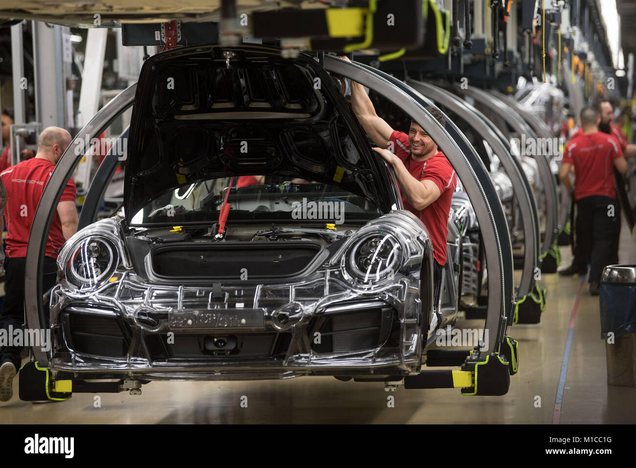 Employees work on cars of the model Porsche 911 at a manufacturing ...