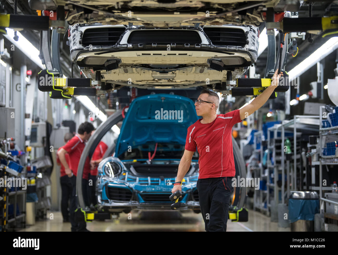 Employees work on a car of the model Boxster 718 at a manufacturing ...