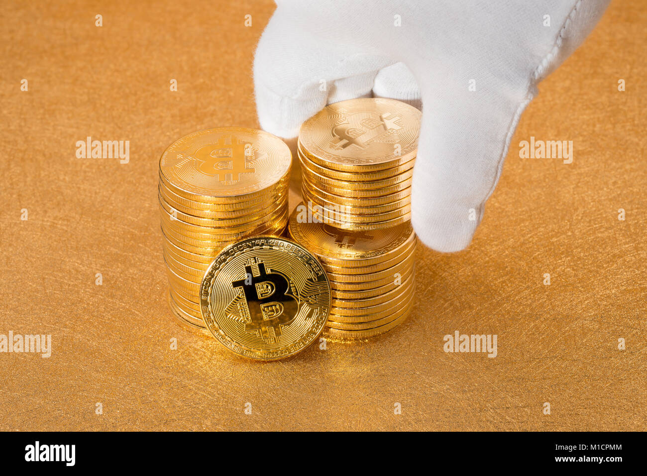 hand loading a pile of bitcoin on golden background Stock Photo - Alamy
