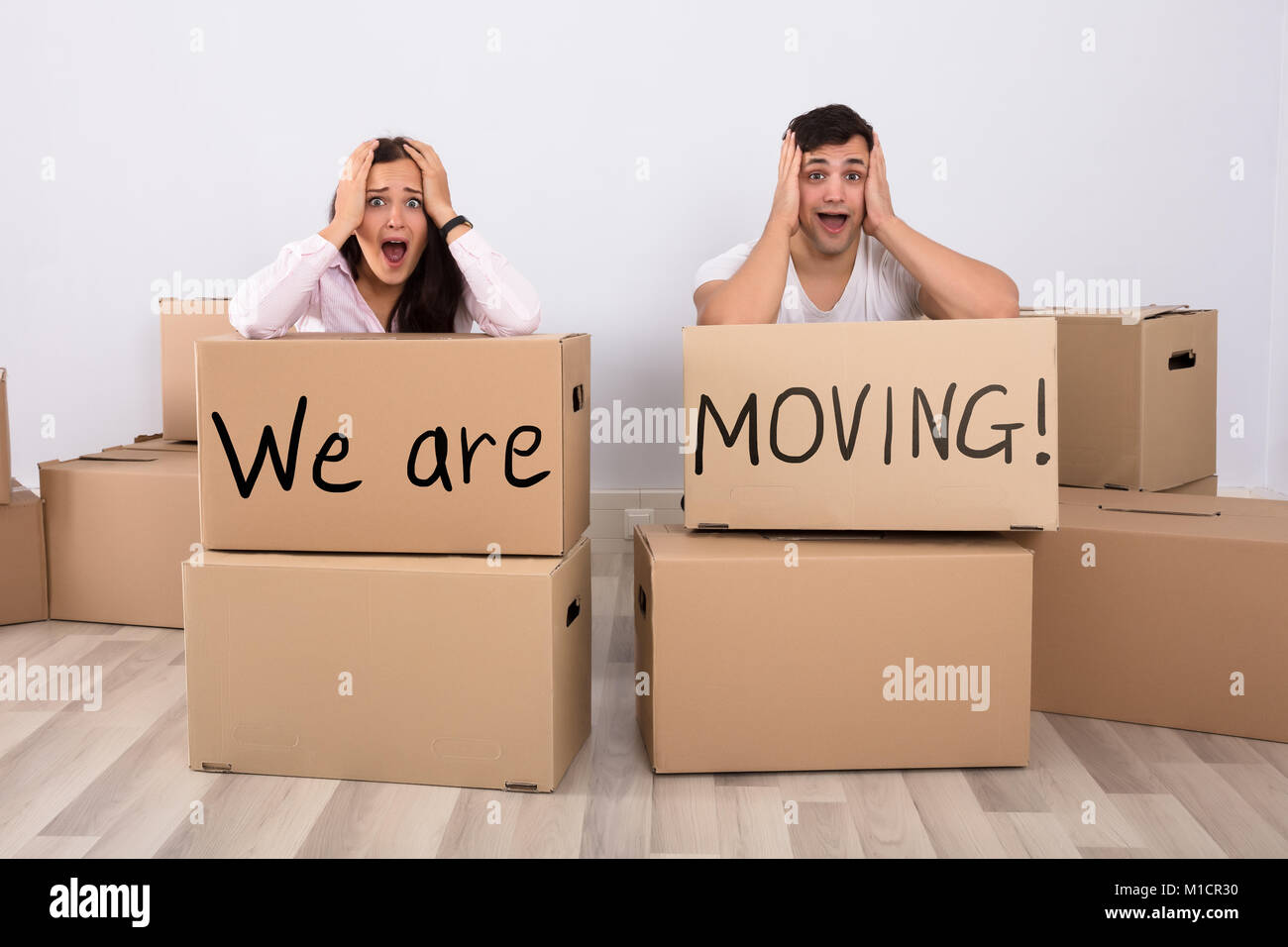 Young Couple Screaming Behind The Cardboard Boxes In Home Stock Photo ...