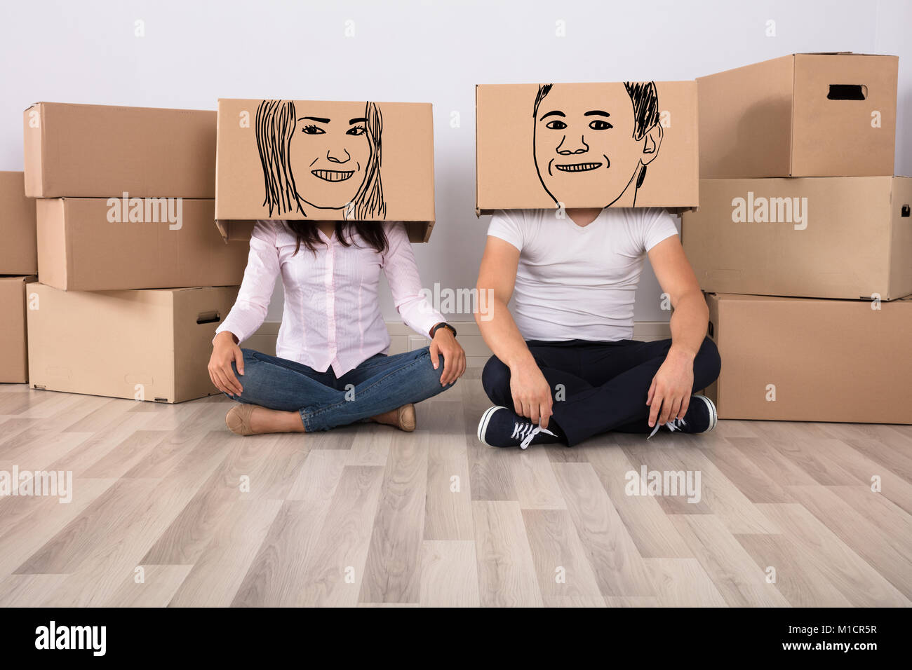 Funny Couple Sitting On Floor Wearing Cardboard Boxes At Home Stock ...