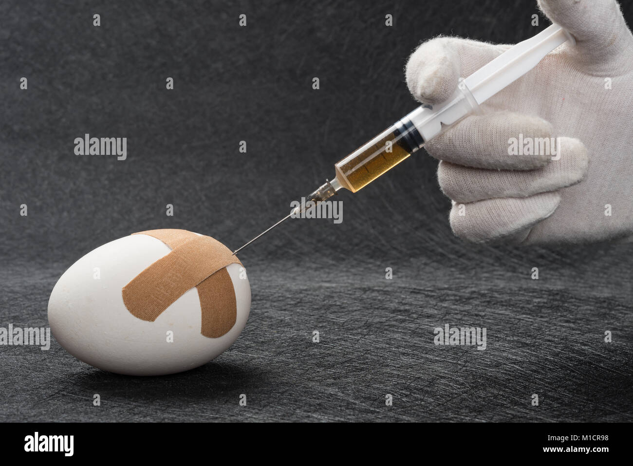 doing injection by medical syringe to an egg with plasters Stock Photo ...