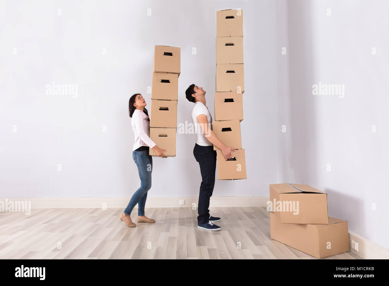 Young Couple Carrying Stack Of Cardboard Boxes In Their New Home Stock ...
