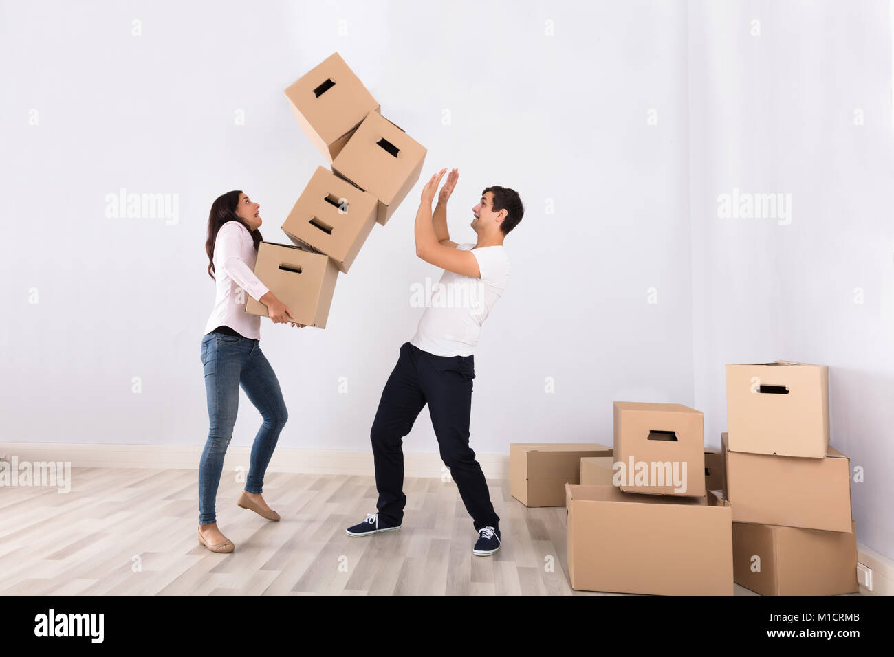 Young Woman Falling Stack Of Cardboard Boxes Over The Man In House ...