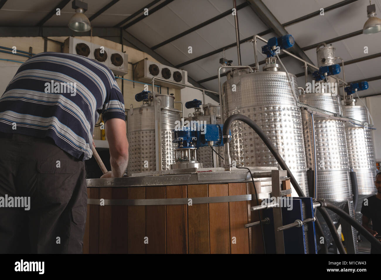 Rear view of male worker stirring gin in distillery at factory Stock ...