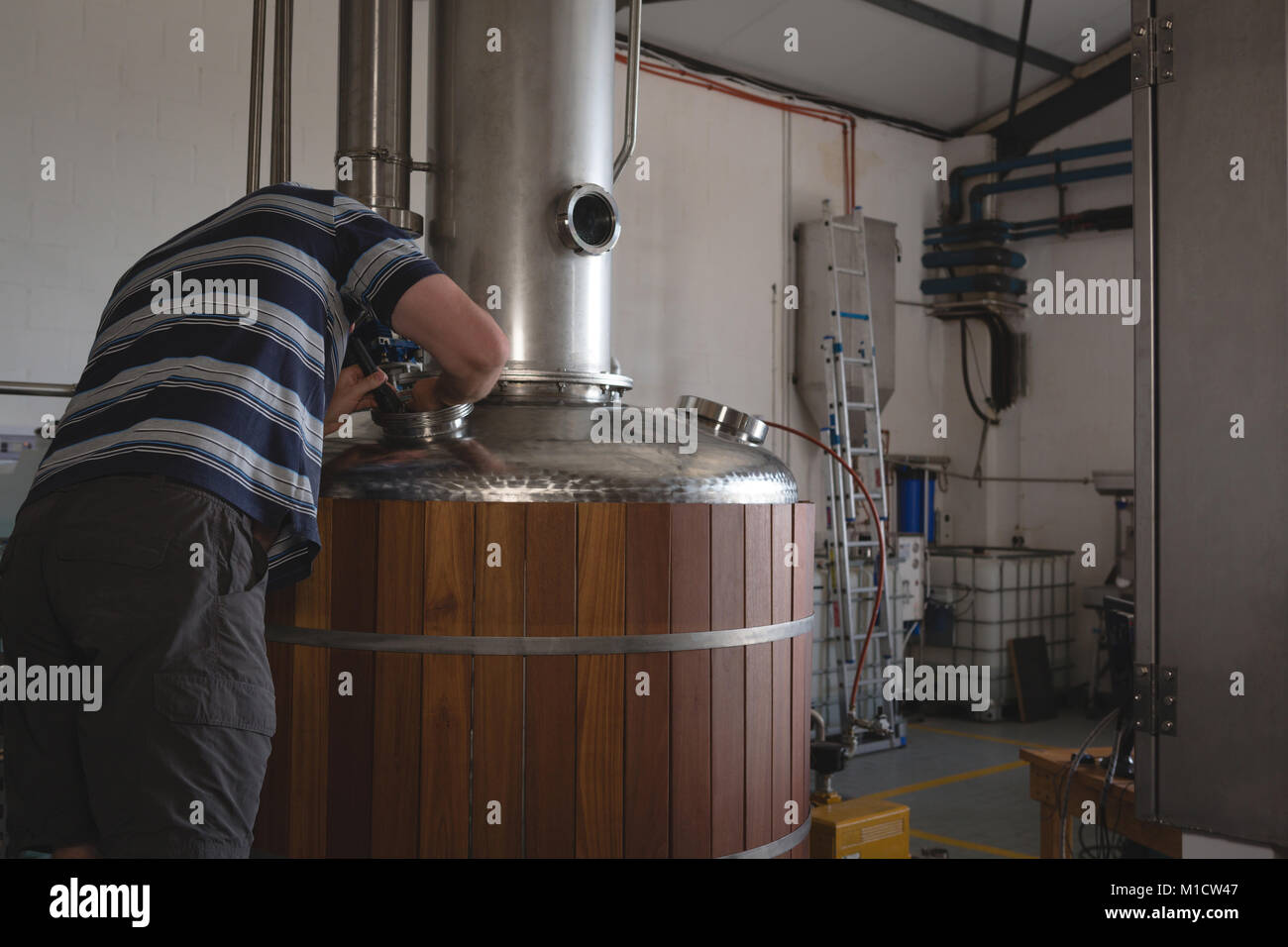 Male worker checking machine of distillery Stock Photo - Alamy