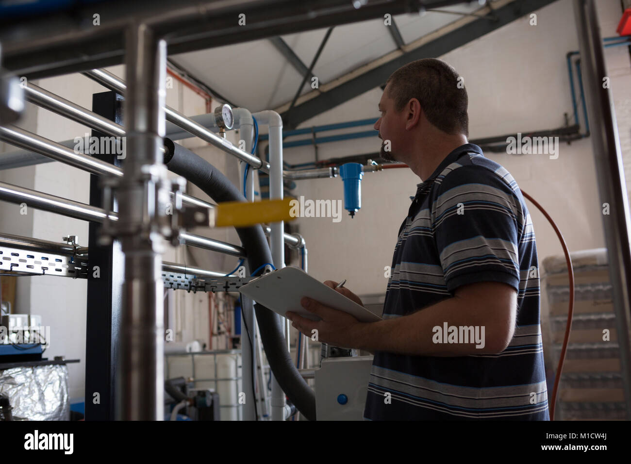 Male worker monitoring a pressure gauge of storage tank Stock Photo - Alamy