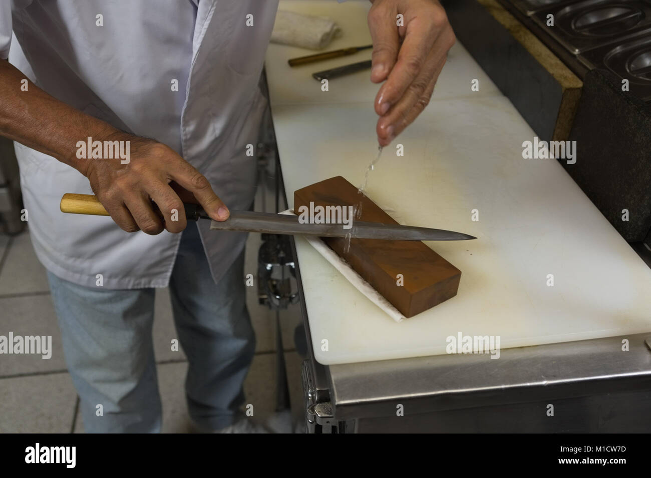 Senior chef holding knife in kitchen Stock Photo - Alamy