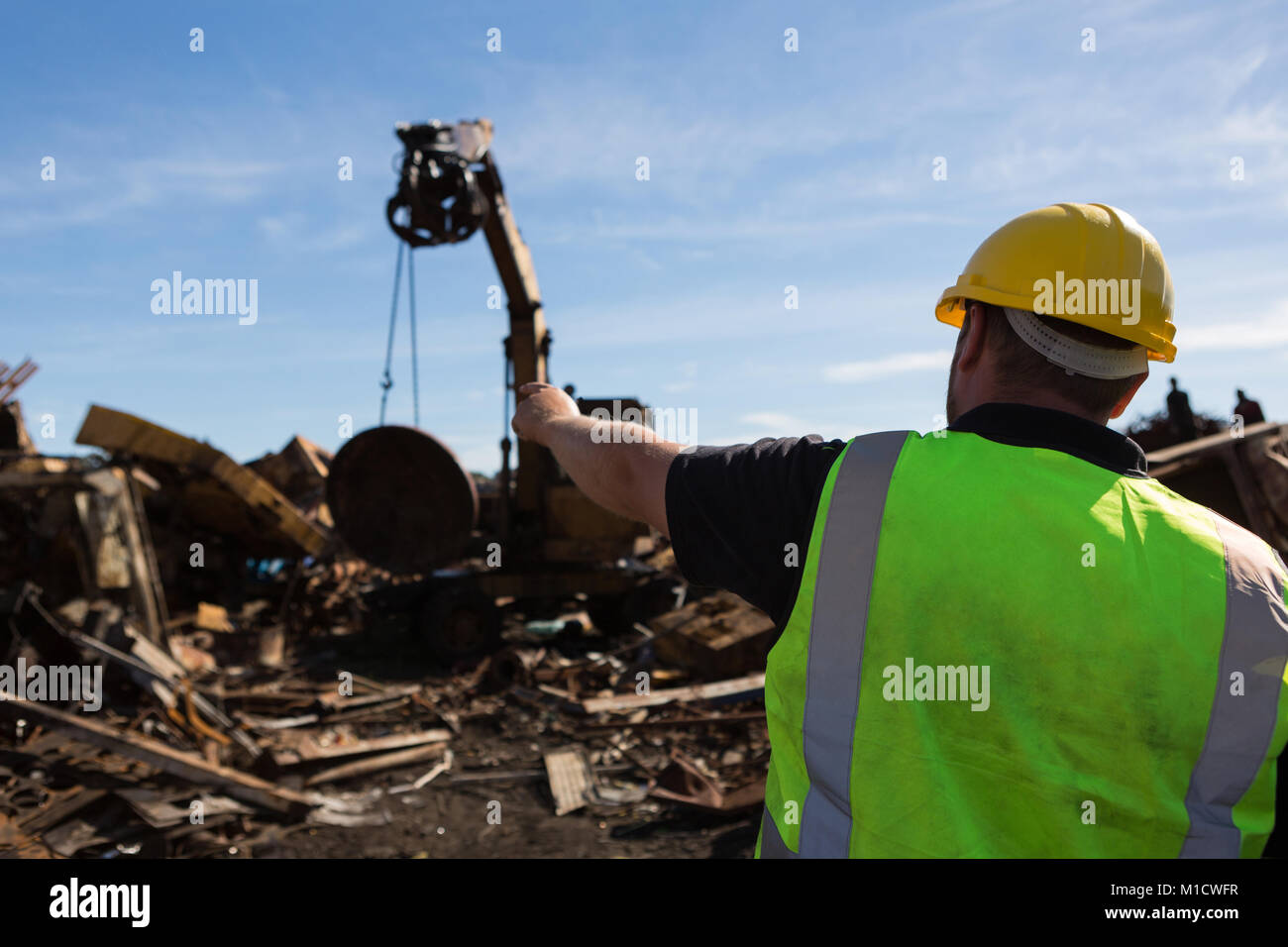 Worker pointing at the trash being lifted by crane Stock Photo - Alamy