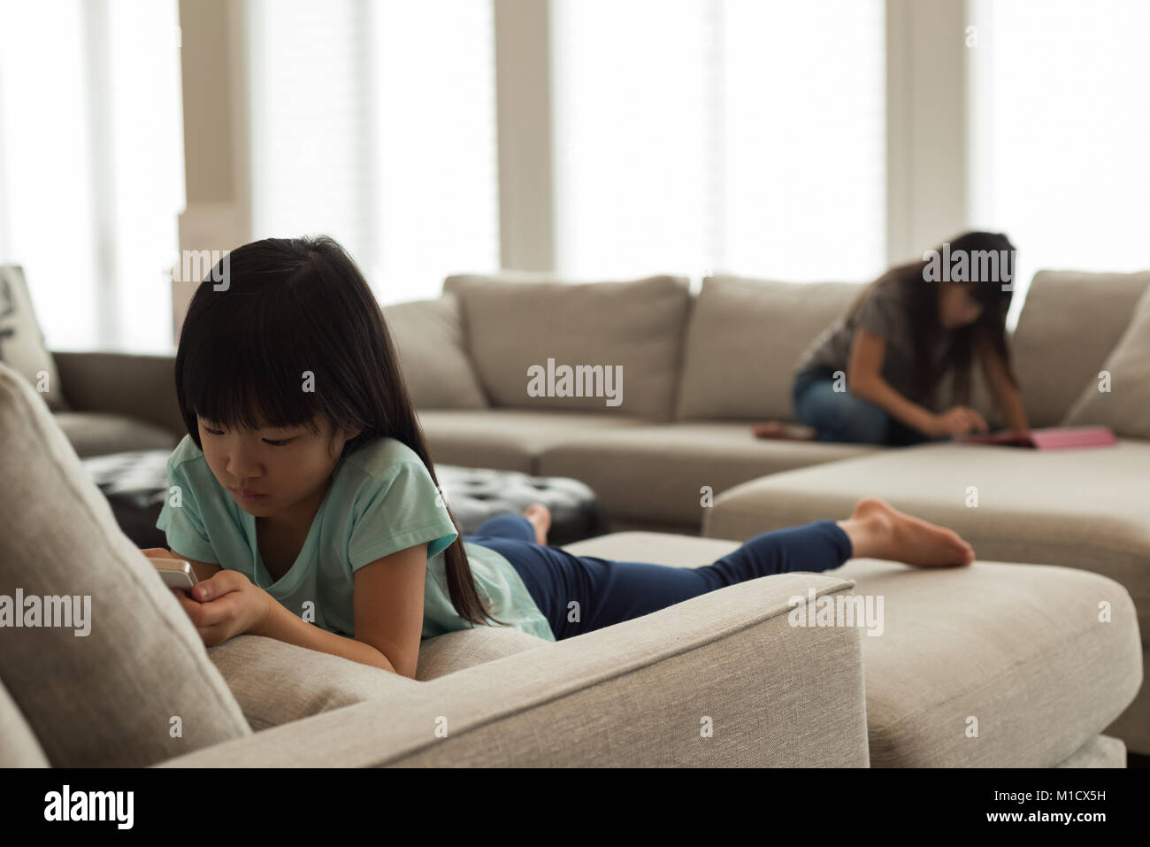 Girl using mobile phone in living room Stock Photo - Alamy