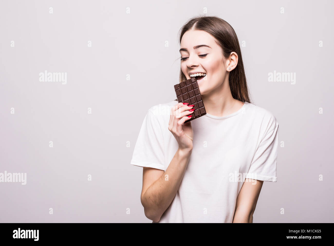smiling teenage girl eating chocolate isolated on gray Stock Photo - Alamy