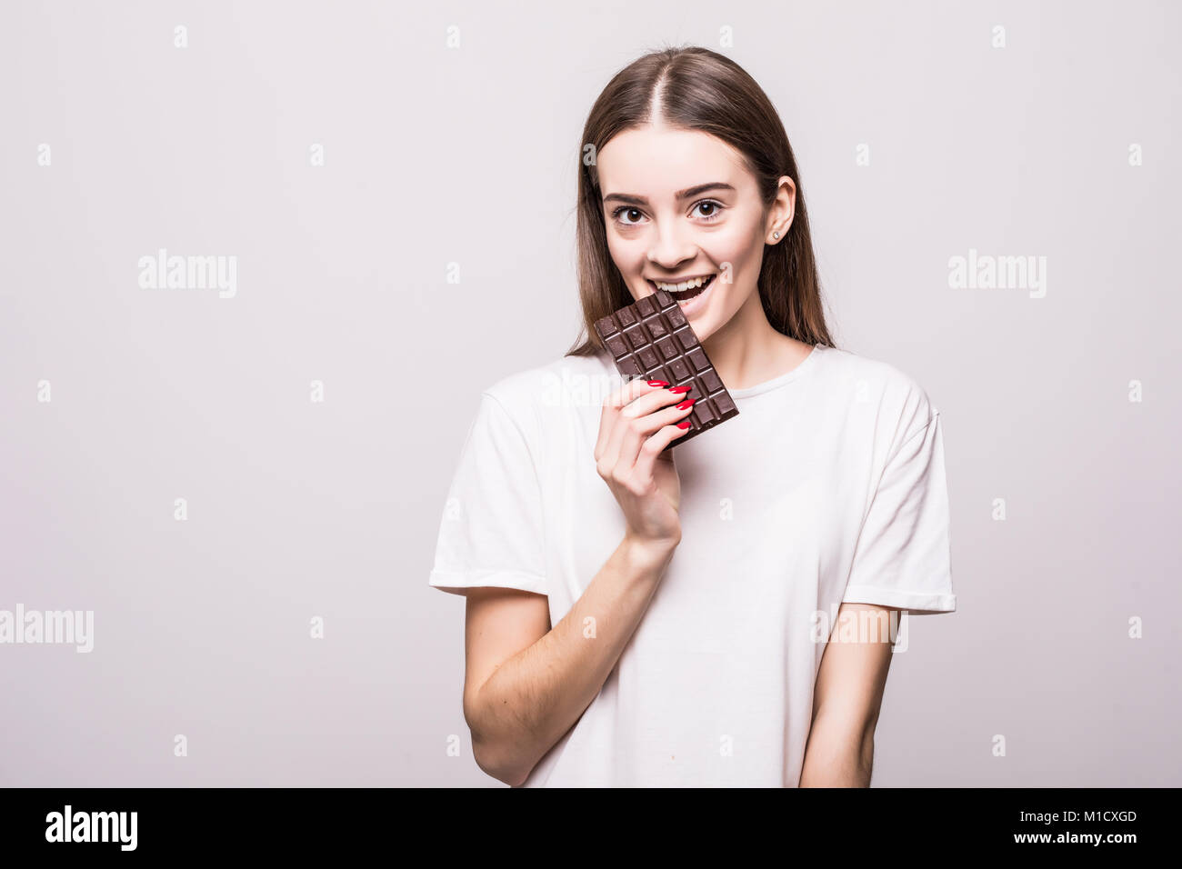 smiling teenage girl eating chocolate isolated on gray Stock Photo - Alamy
