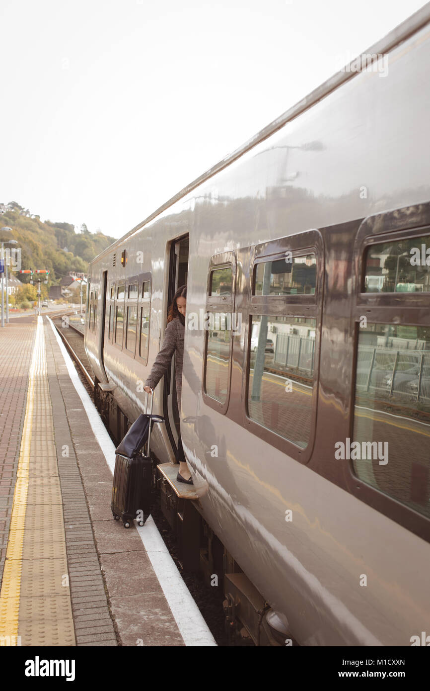 Woman getting in the train with luggage Stock Photo - Alamy
