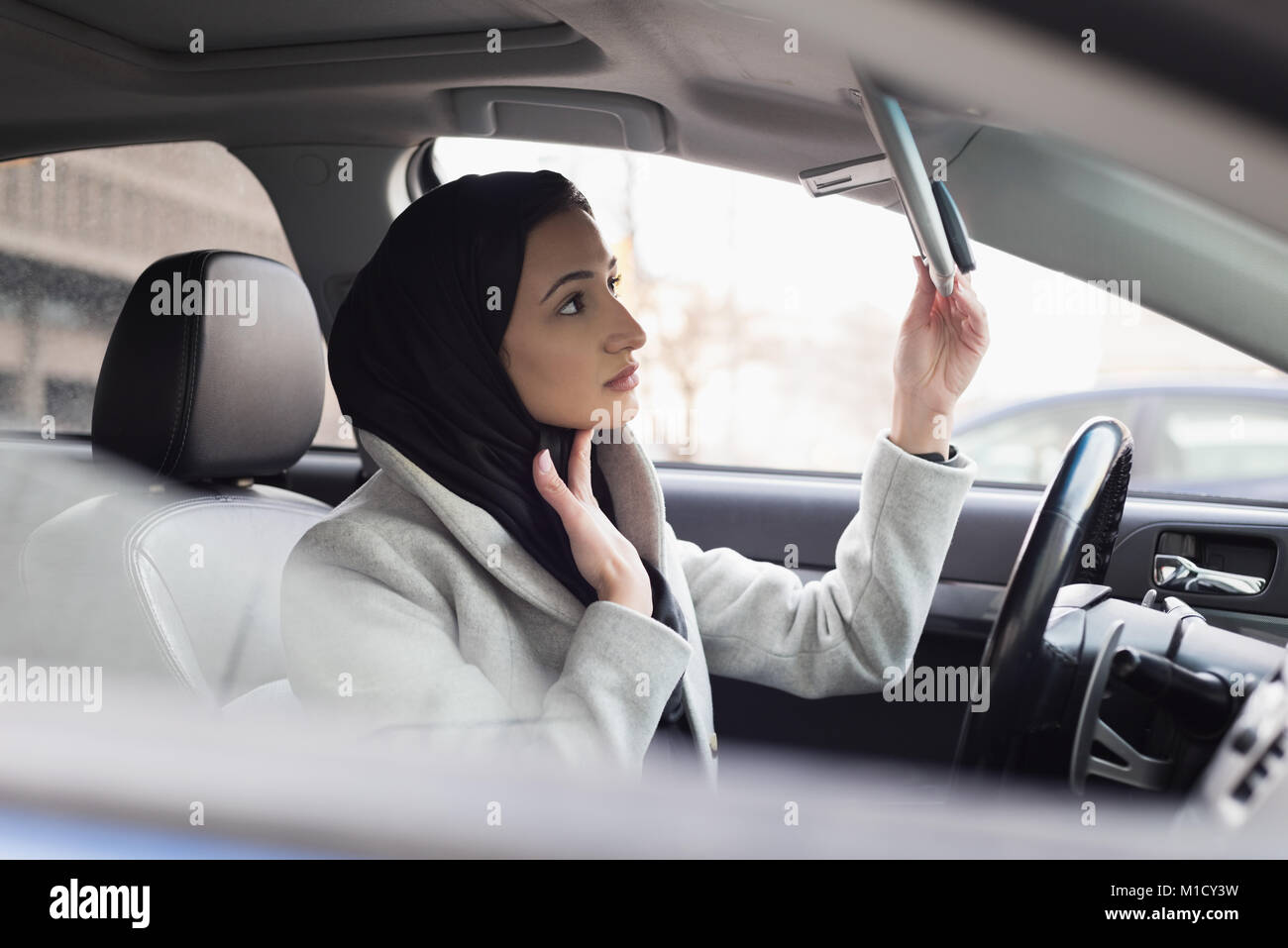 Woman in hijab looking at rear-view mirror Stock Photo - Alamy
