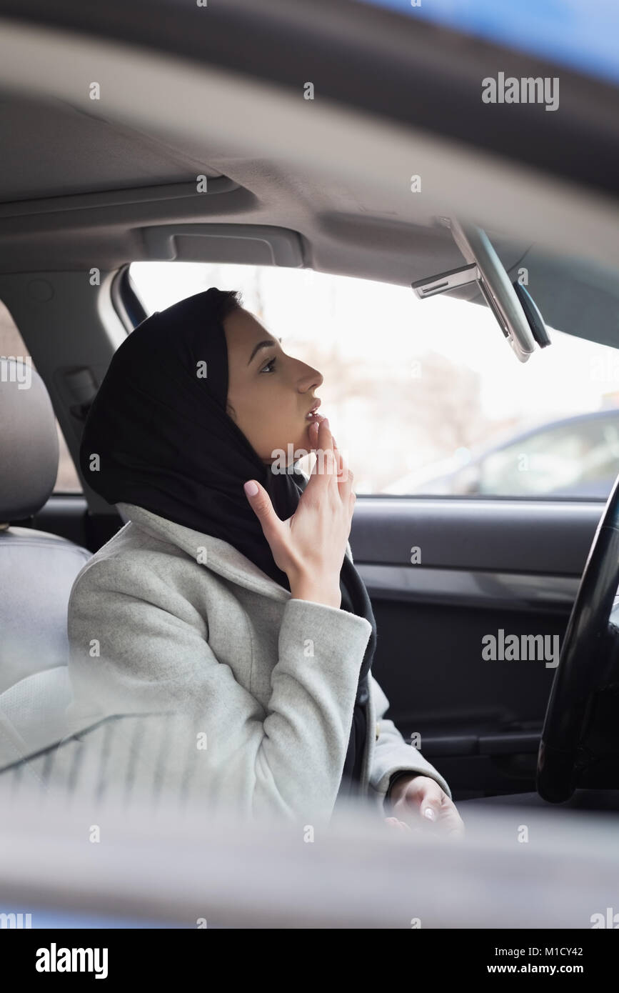 Woman in hijab looking at rear-view mirror Stock Photo - Alamy