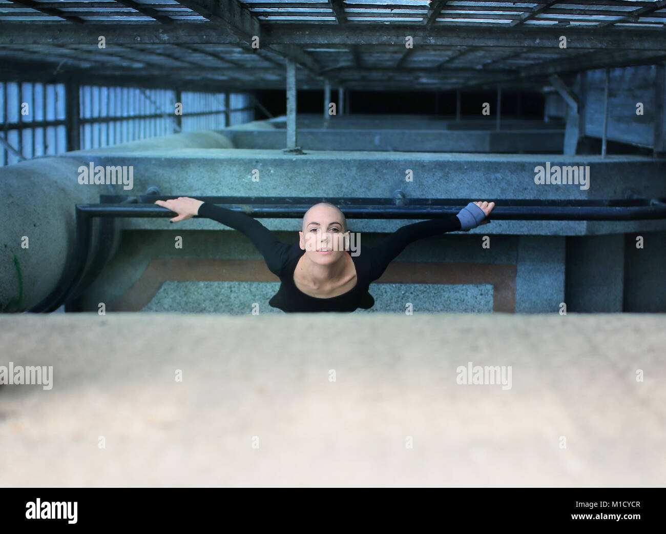 Beautiful bald woman looking up from the floor below and leaning on a ...