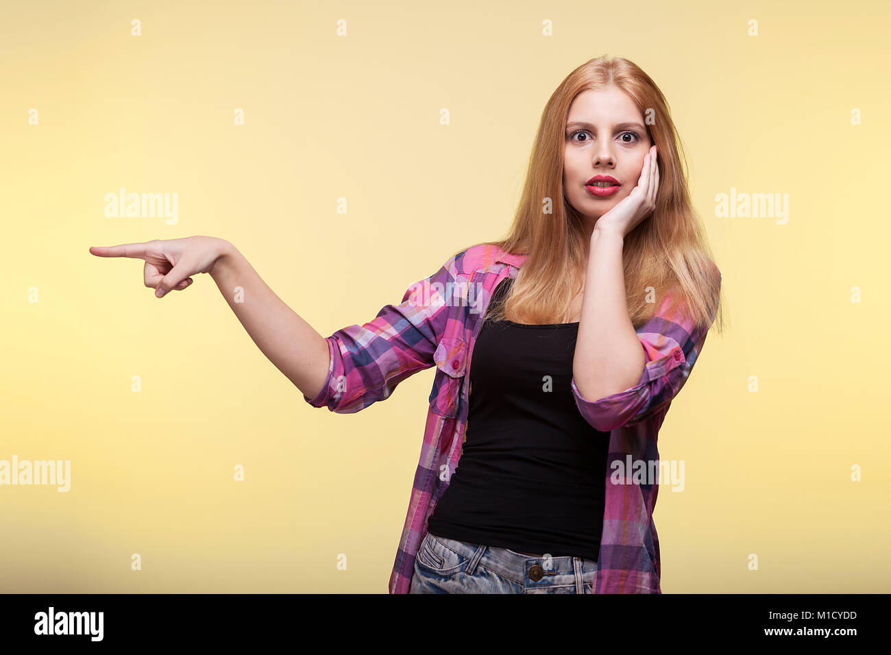 Surprised young woman pointing to her right Stock Photo - Alamy