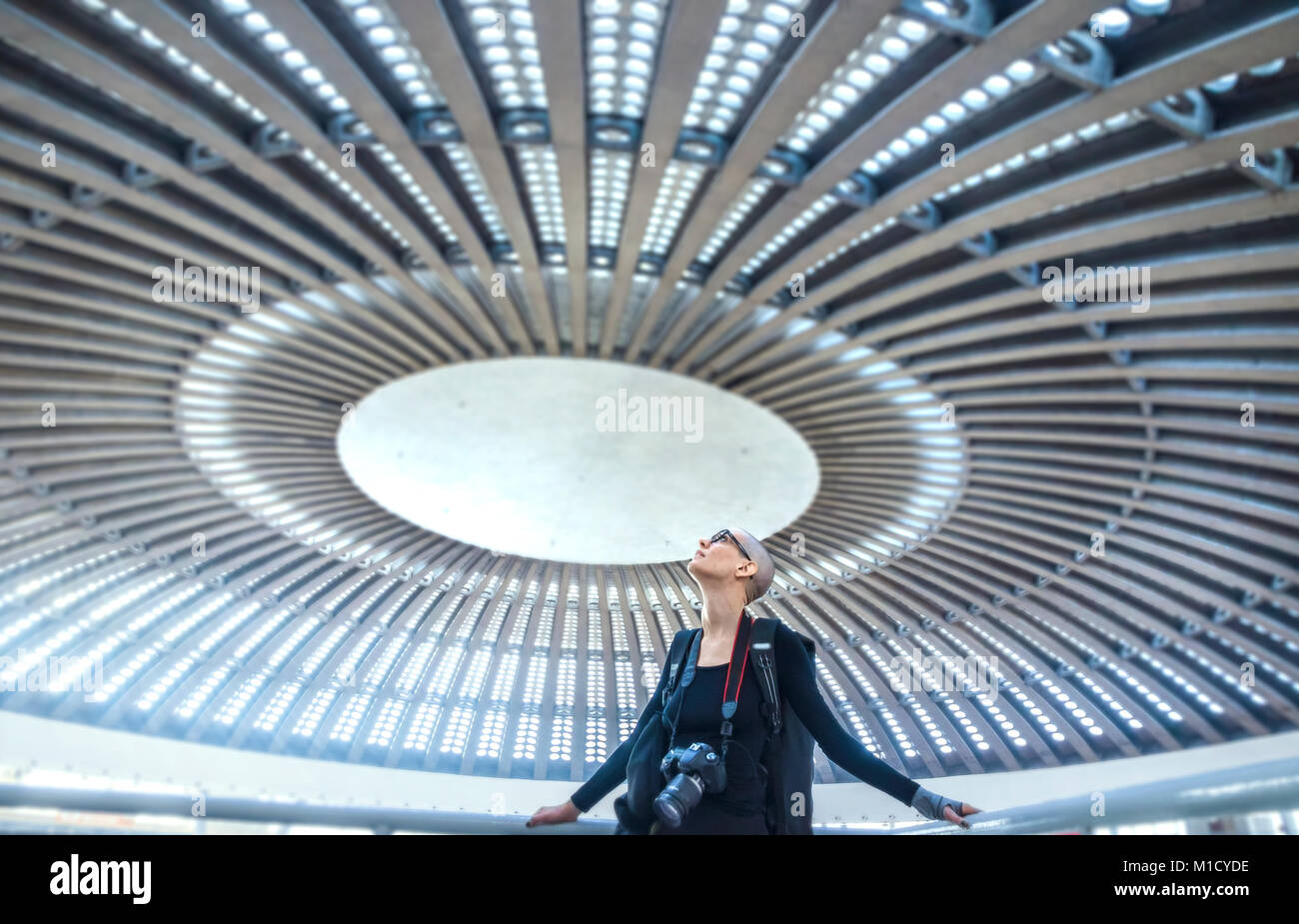 A female photographer admiring a huge circular concert hall ceiling ...