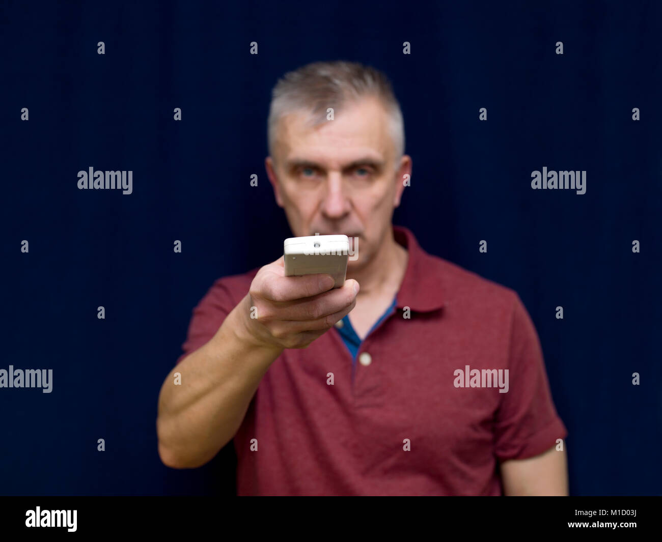 Man pointing remote control, front studio shot on blue Stock Photo - Alamy