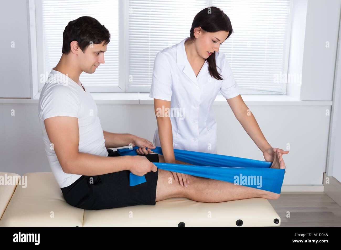 Female Therapist Assisting Male Patient While Stretching His Leg In ...