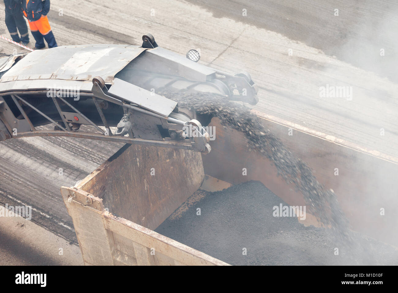 Road works. Asphalt removing machine loading powdered asphalt on the ...