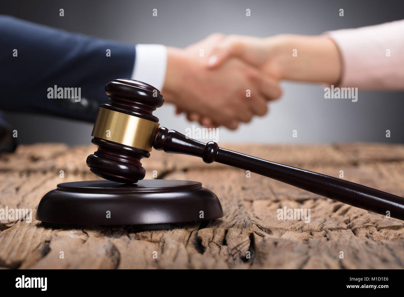 Close-up Of A Gavel On Wooden Desk In Front Of Businesspeople Shaking ...
