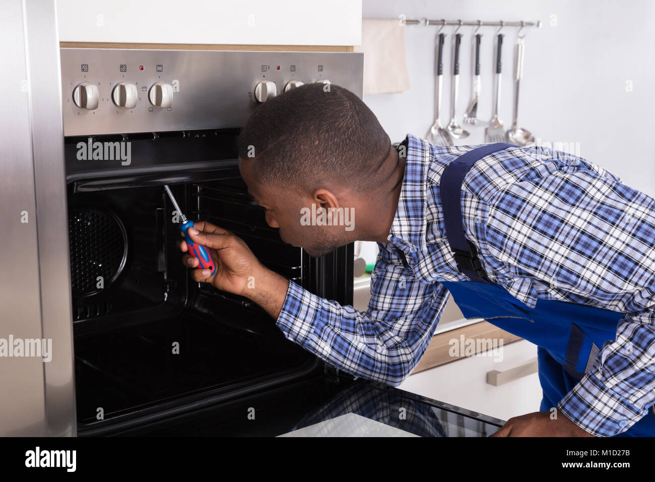 Young Repairman With Screwdriver Fixing Kitchen Oven Stock Photo - Alamy