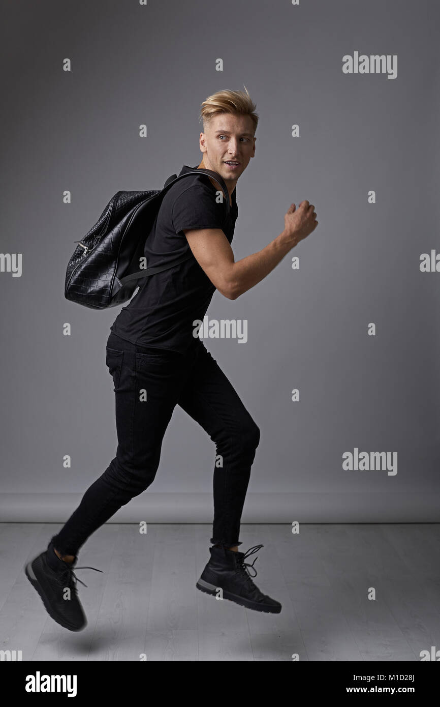 Handsome young man running with a backpack on shoulders Stock Photo - Alamy