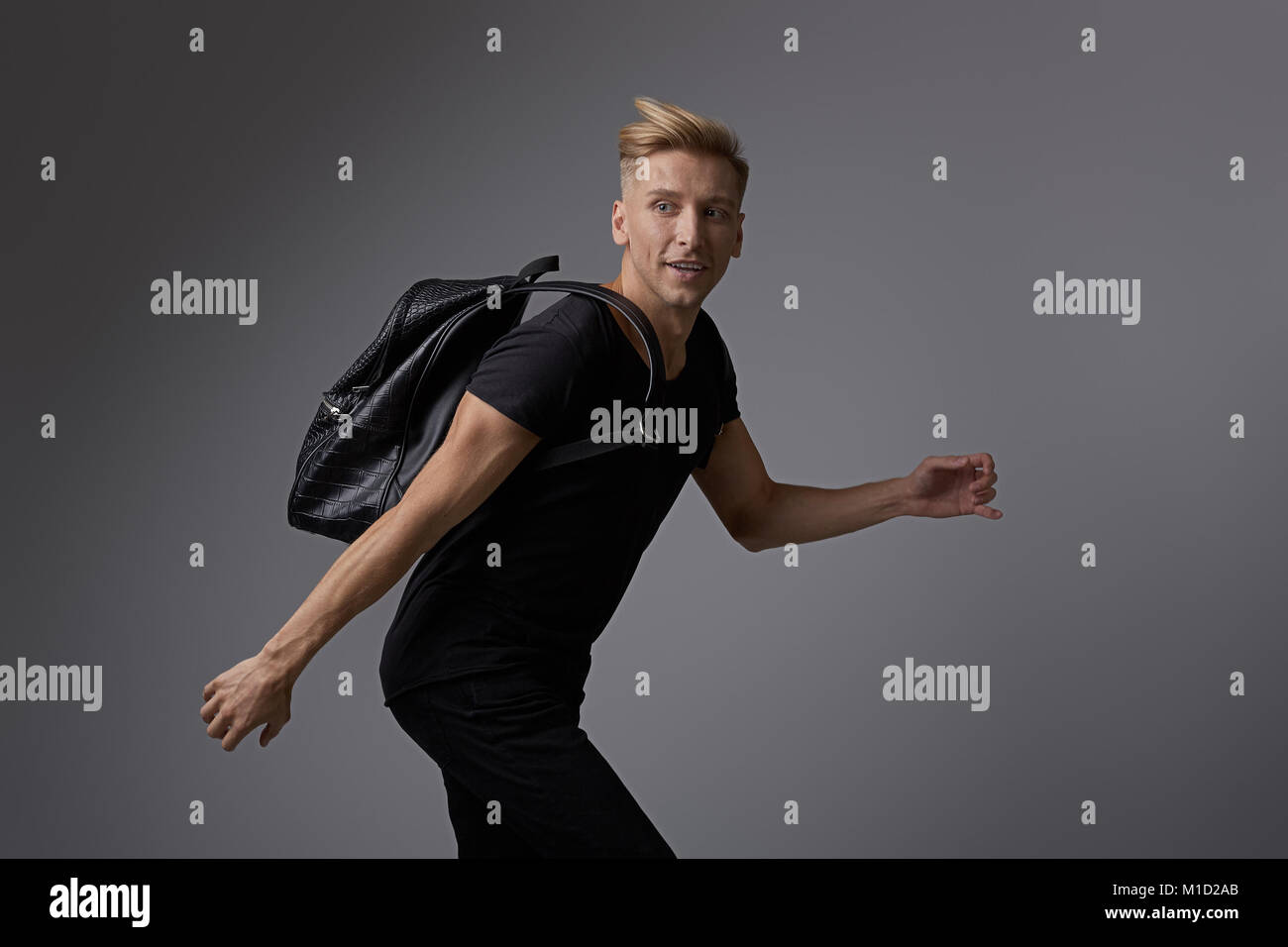 Handsome young man running with a backpack on shoulders Stock Photo - Alamy