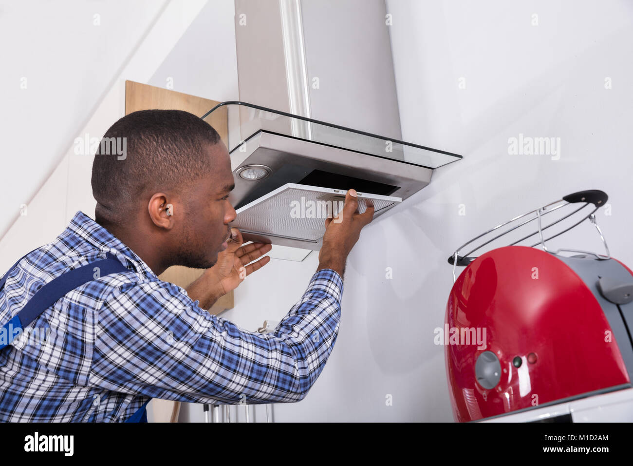 Young African Male Fixing Kitchen Extractor Filter In Kitchen Room ...