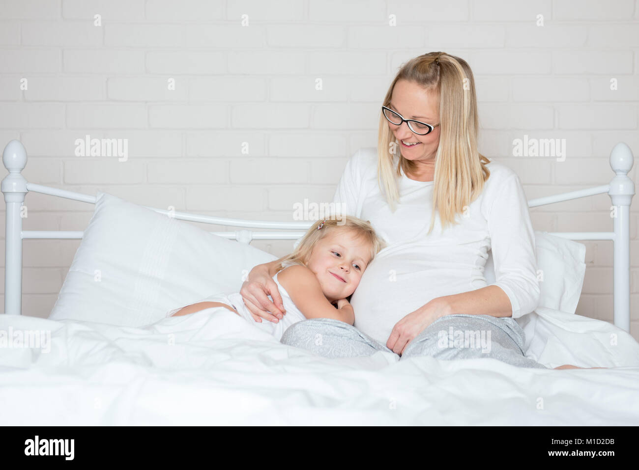 Happy daughter snuggle up to her pregnant mother Stock Photo - Alamy