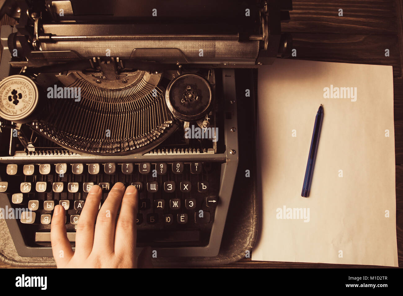 hand on a typewriter on a wooden background and a white sheet and ...