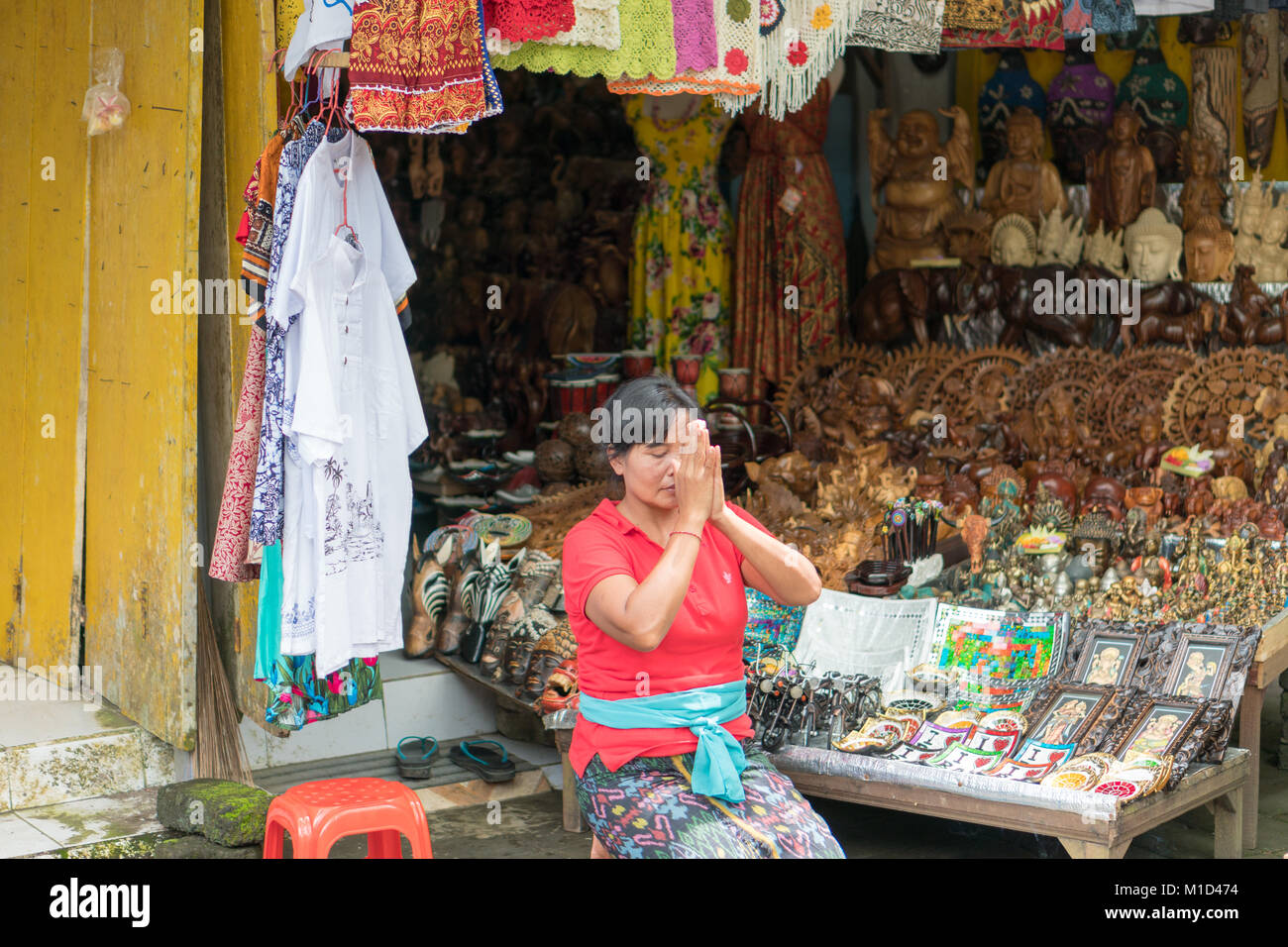 Praying in front of tourist stall, Bali, Indonesia Stock Photo - Alamy